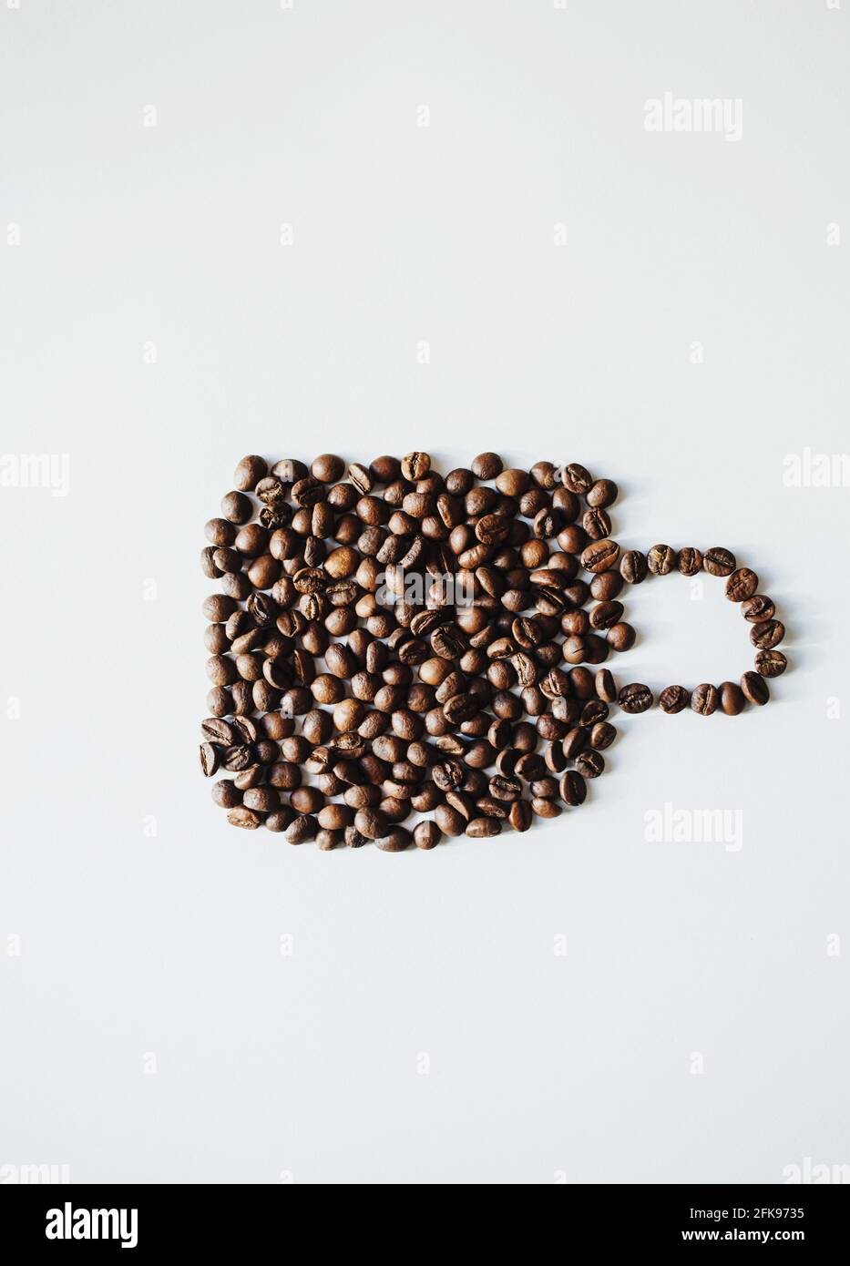 Brown coffee beans in form cup on white background Stock Photo - Alamy
