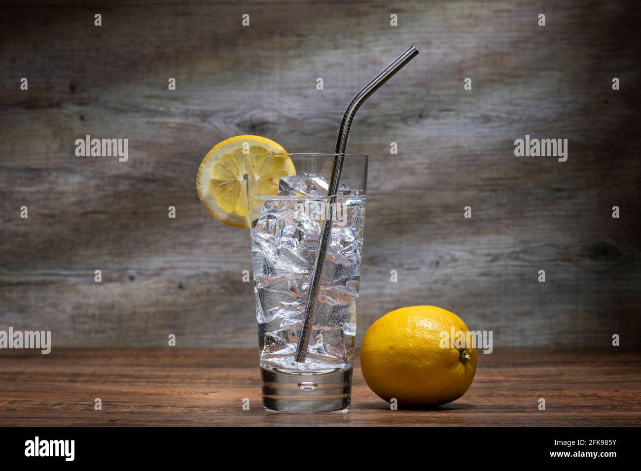 Glass of water with ice and lemon and a stainless steel straw in a ...