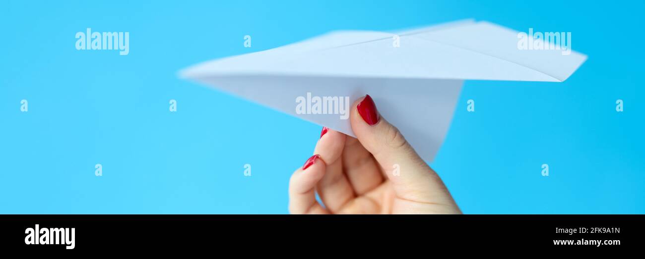 Female hand holding paper plane on blue background Stock Photo - Alamy