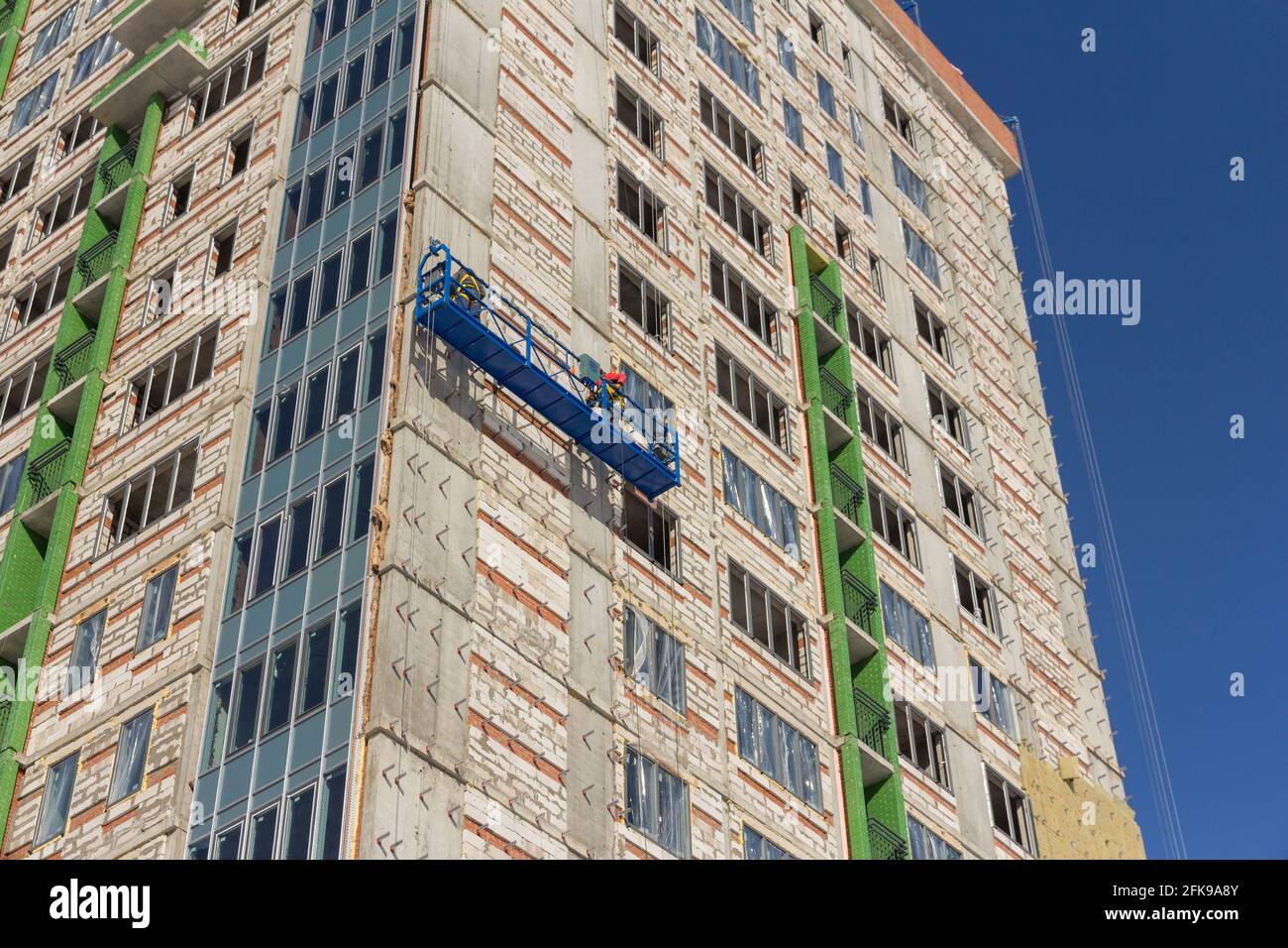 Construction suspended cradle. Construction cradle with workers on the ...