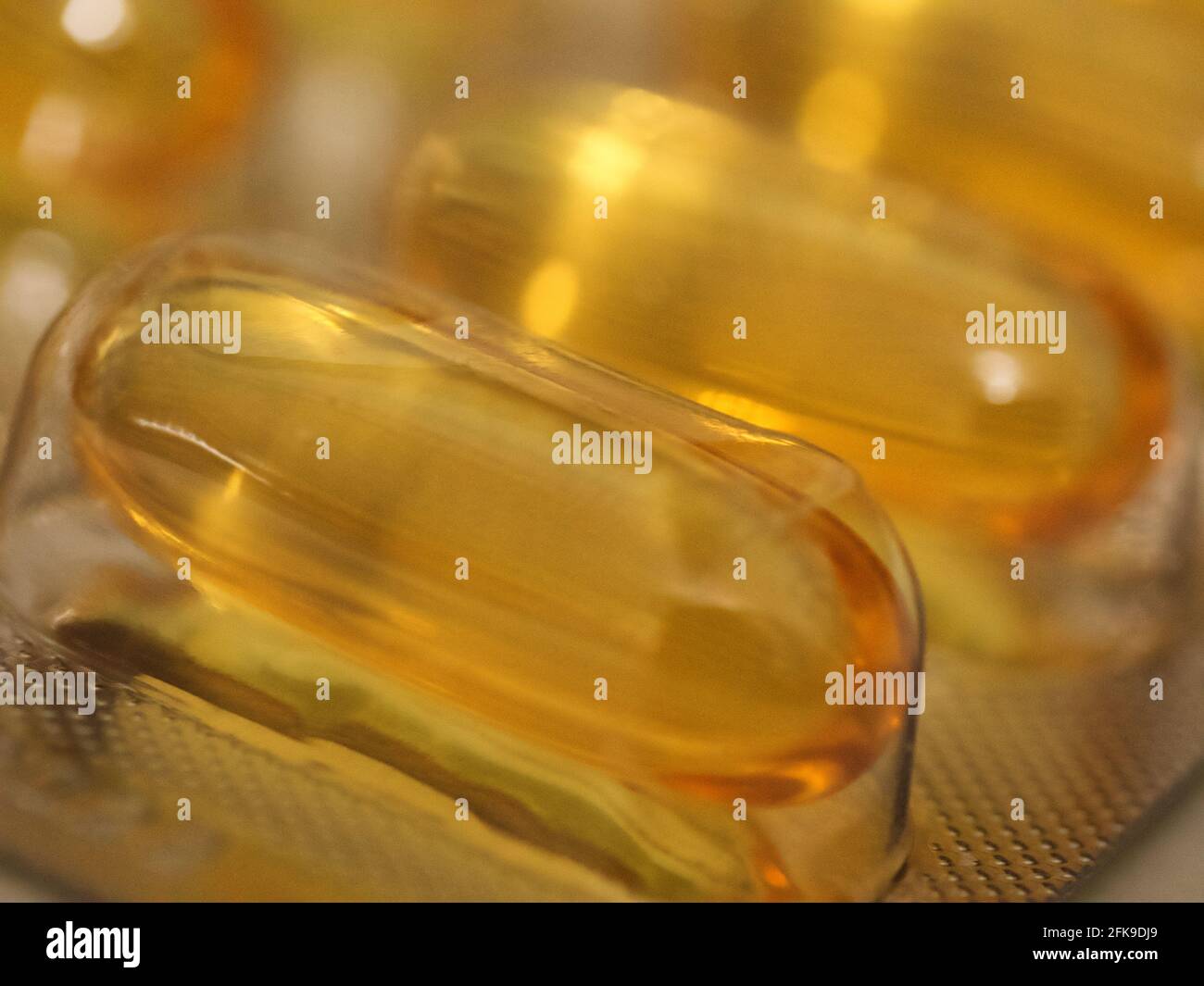 A package of yellow capsule pills, photographed in close-up. Medicinal ...