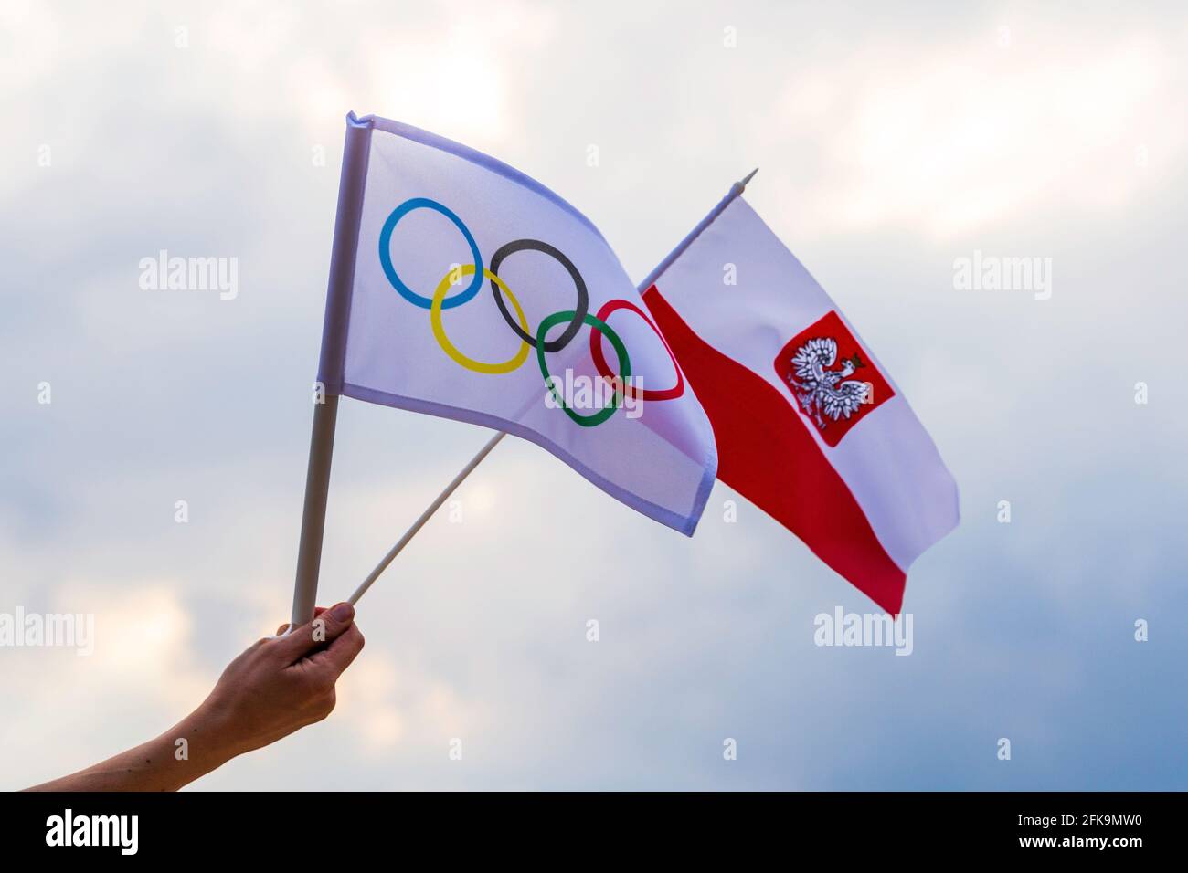 Fan waving the national flag of Poland and the Olympic flag with symbol ...
