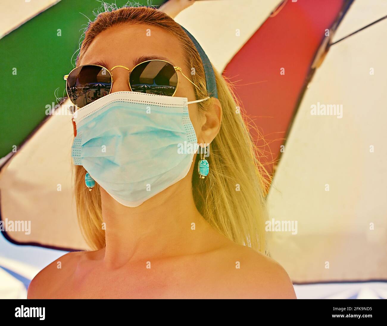 Italian Girl wearing a face mask under a beach umbrella with the ...