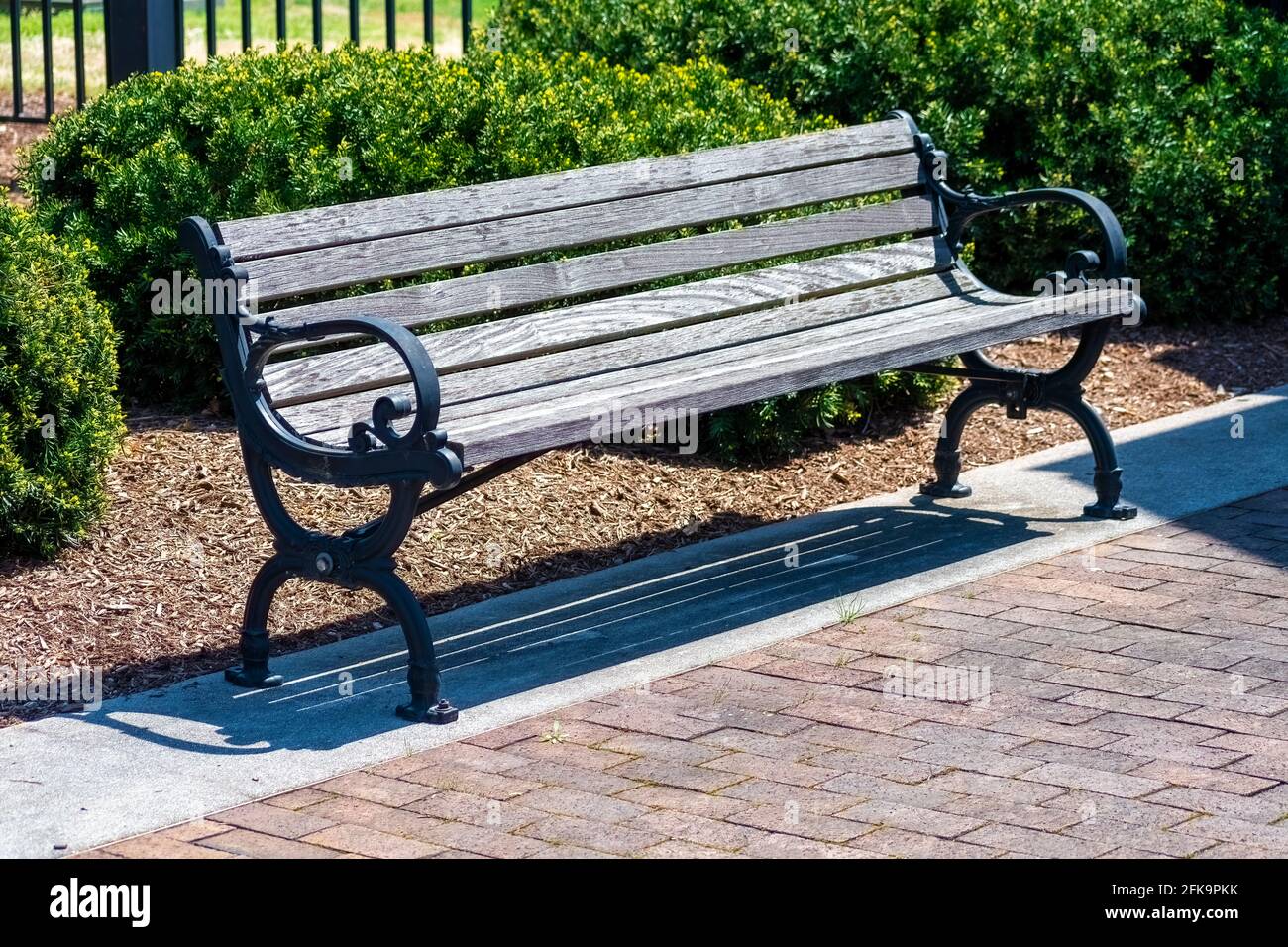 A comfortable park bench that shows signs of aging. The wood is gray ...