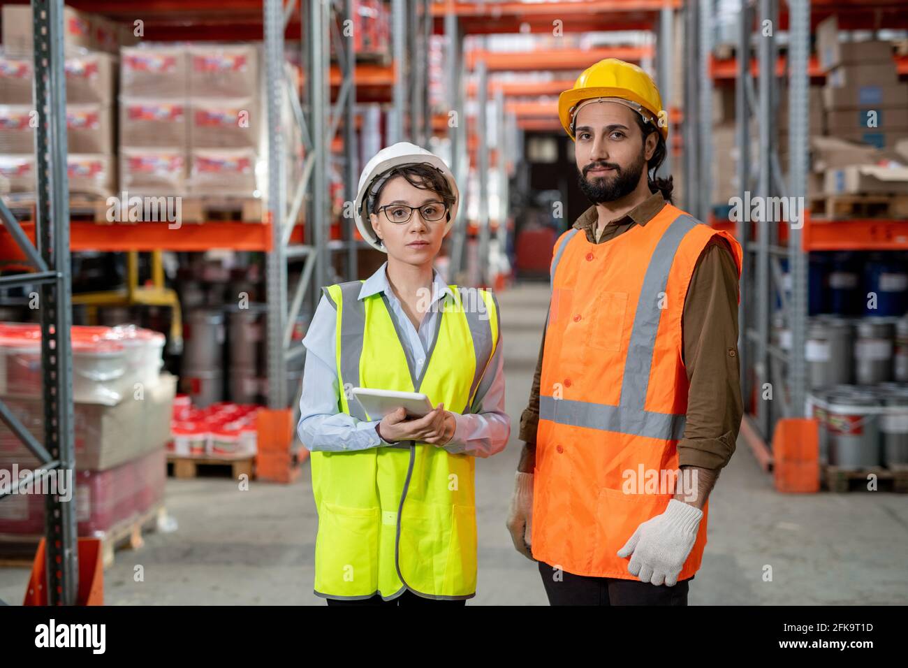 Portrait of content young workers in reflective vests and hardhats ...