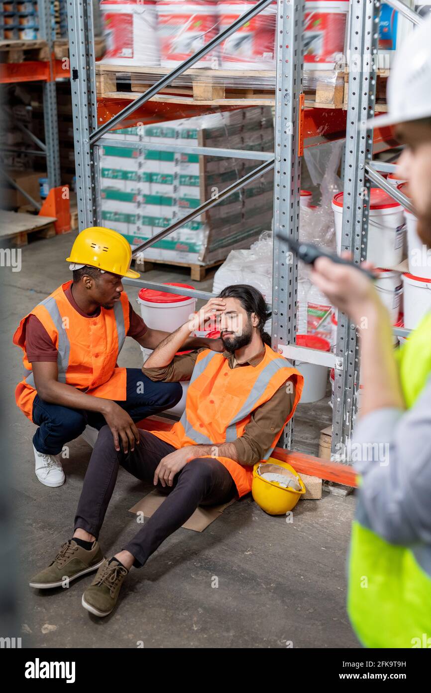 Upset African-American guy in yellow hardhat supporting colleague who ...