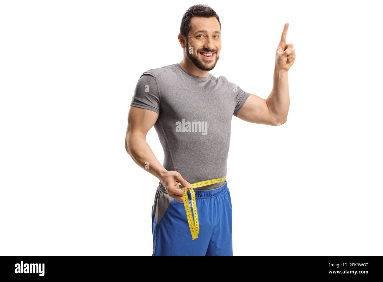 Young man measuring his waist and pointing up isolated on white ...