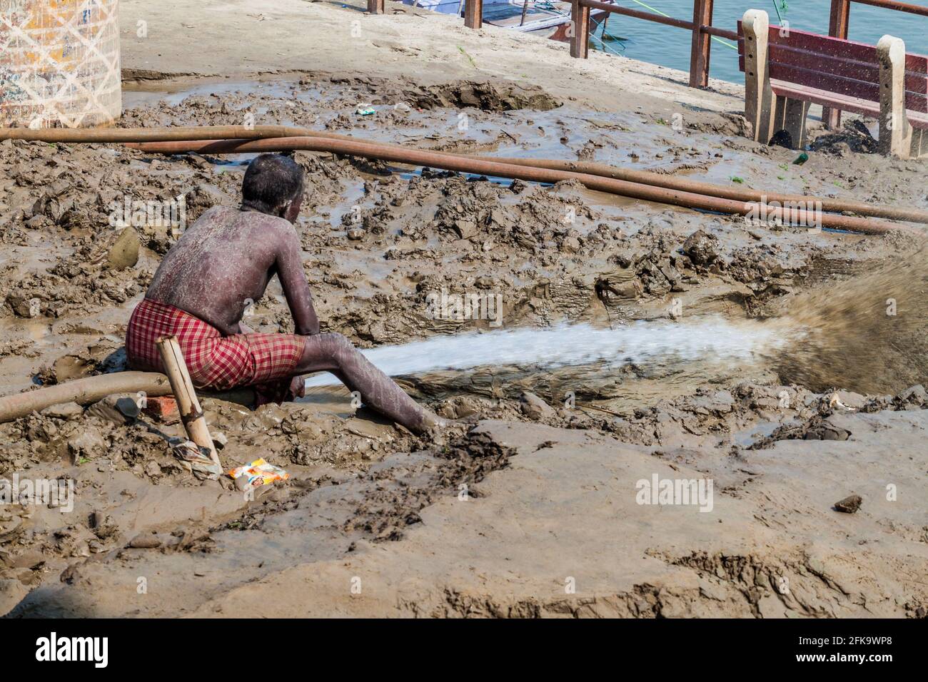 VARANASI, INDIA - OCTOBER 25, 2016: Local man cleans mud sediments at ...