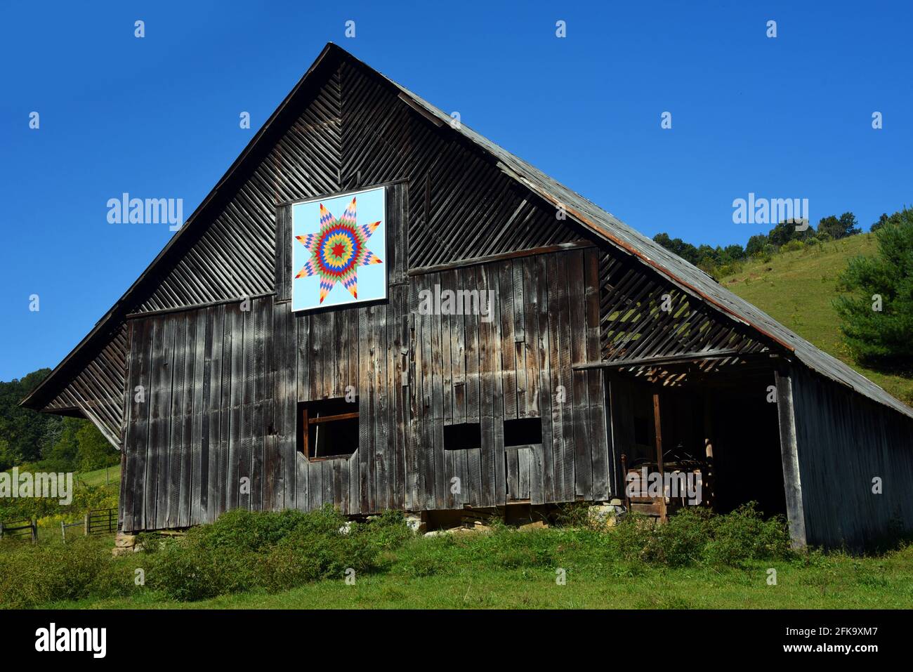 Rustic, weathered and old grey barn has quilt square mounted over loft ...