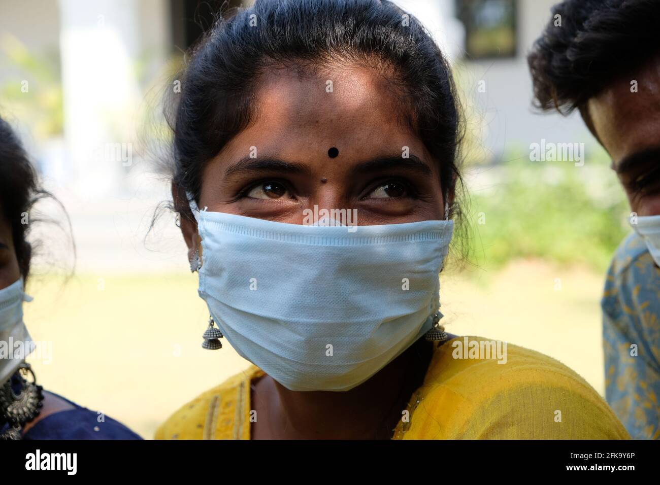 Portrait of a young Indian female wearing a medical face mask in a park ...