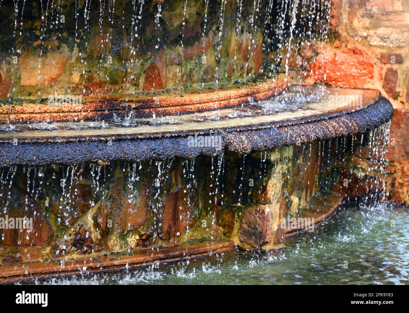 Water fountain is double tiered and water drips down from rim to rim ...