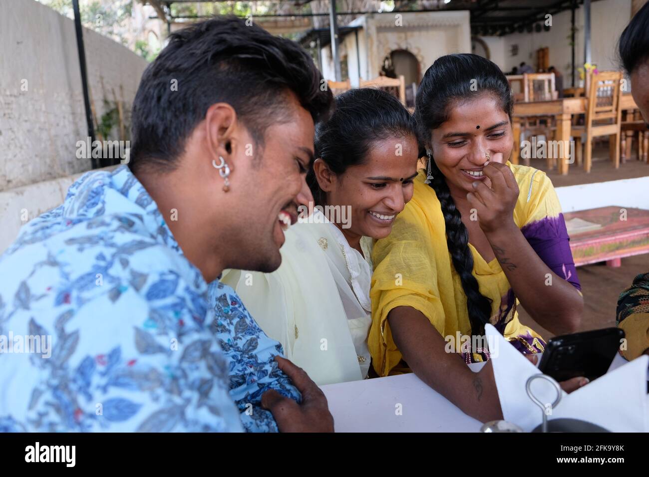 Group of cheerful Indian friends spending time in a cafe and watching ...