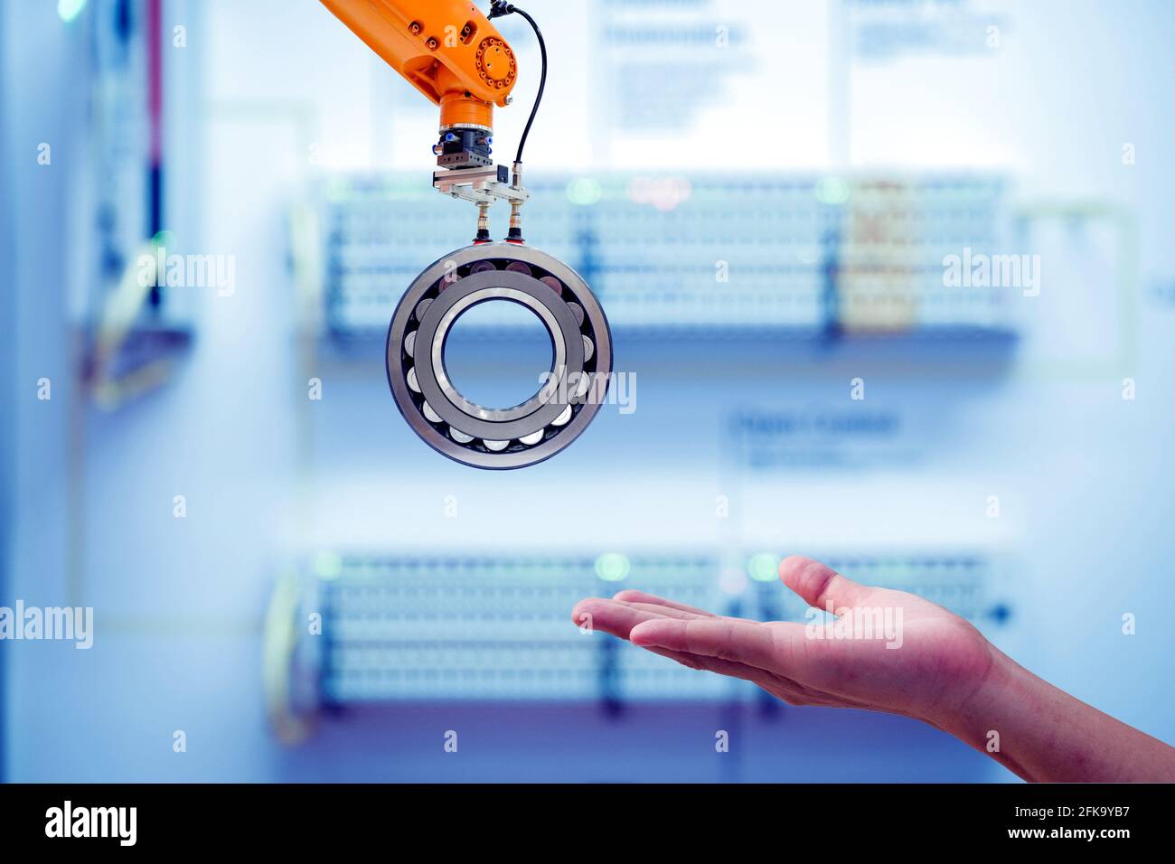 Close-up Industrial robotic gripping a metalwork for send to human hand ...