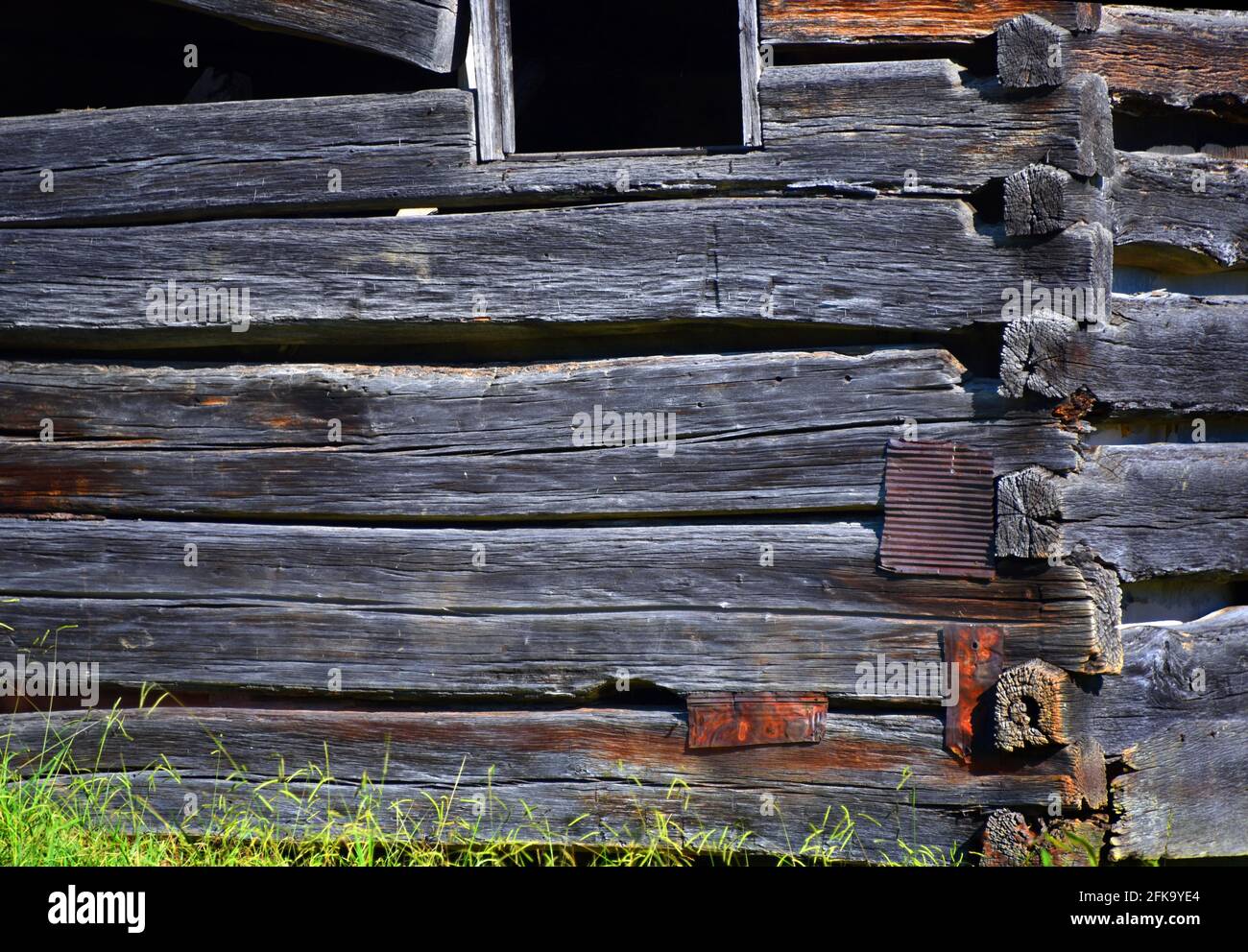 Log barn has the corner notches but unusual tin patches on the exterior ...