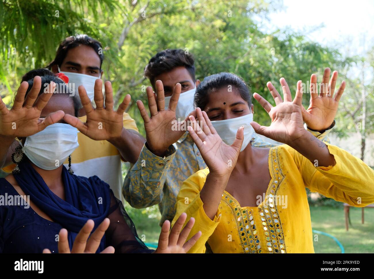Indian people in medical face masks standing outdoors showing their ...