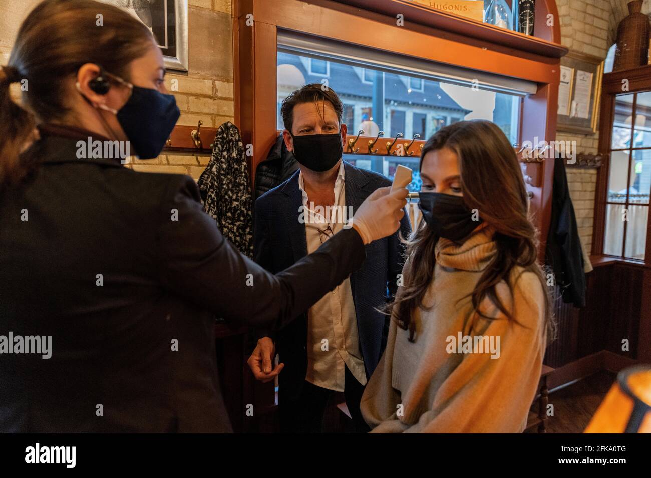 The hostess at a restaurant take the temperature of a female guest upon ...
