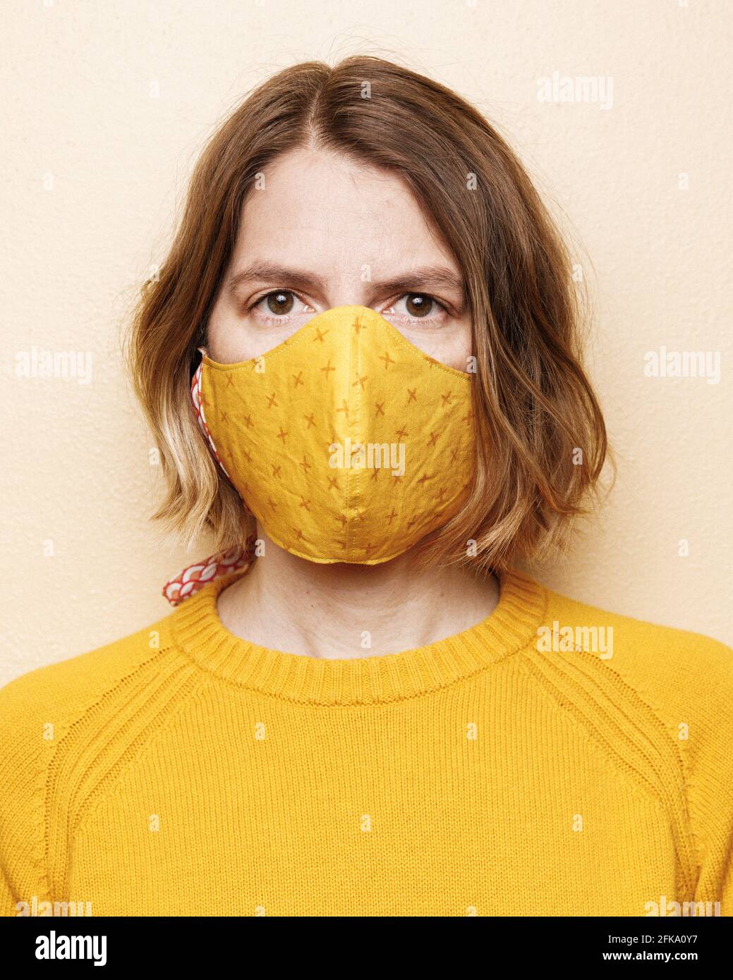 portrait of a woman with a gold colored sweater and chin length hair ...