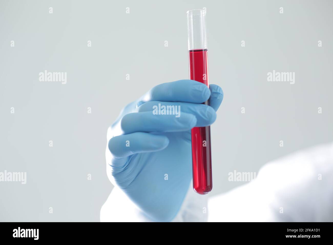 Hand holding test tube with red liquid Stock Photo - Alamy