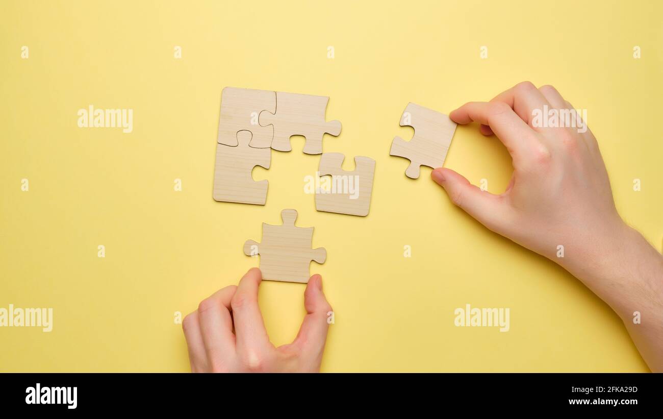 Persons assemble a wooden puzzle and connects the last piece. Staff ...