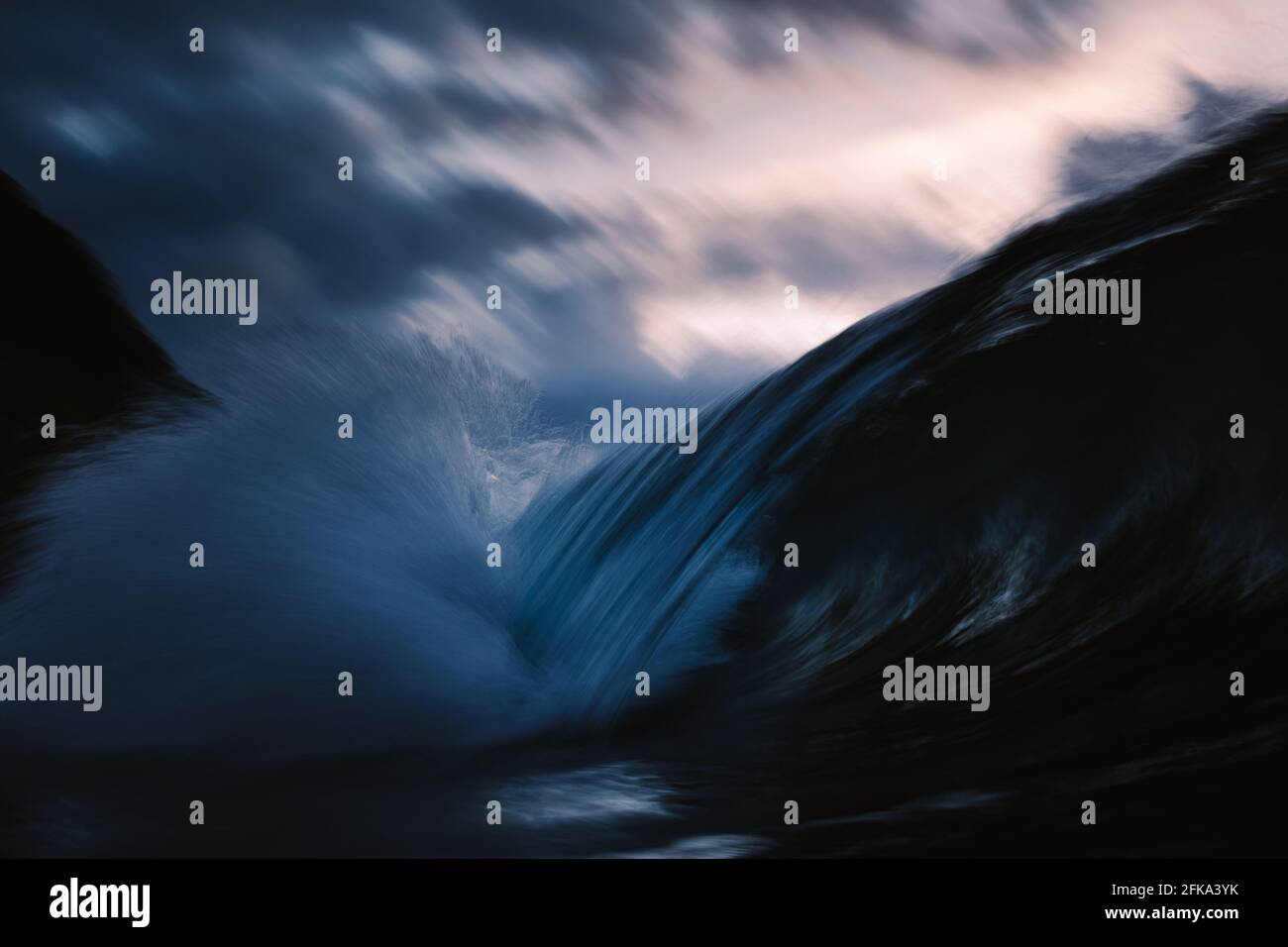 Wave breaking with slow exposure under clouds Stock Photo - Alamy