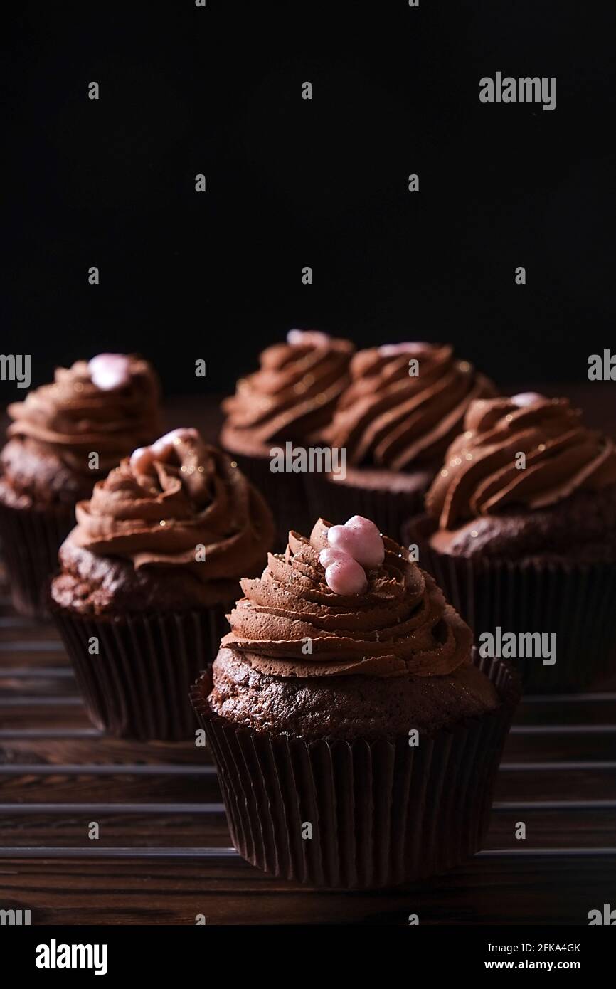 Delicious dark chocolate buttercup cupcakes on wooden textured table w ...