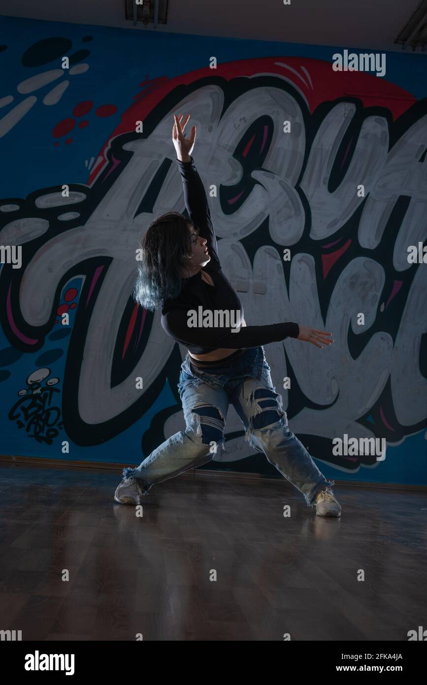 Female dancer in activewear squatting on the floor of modern dance ...