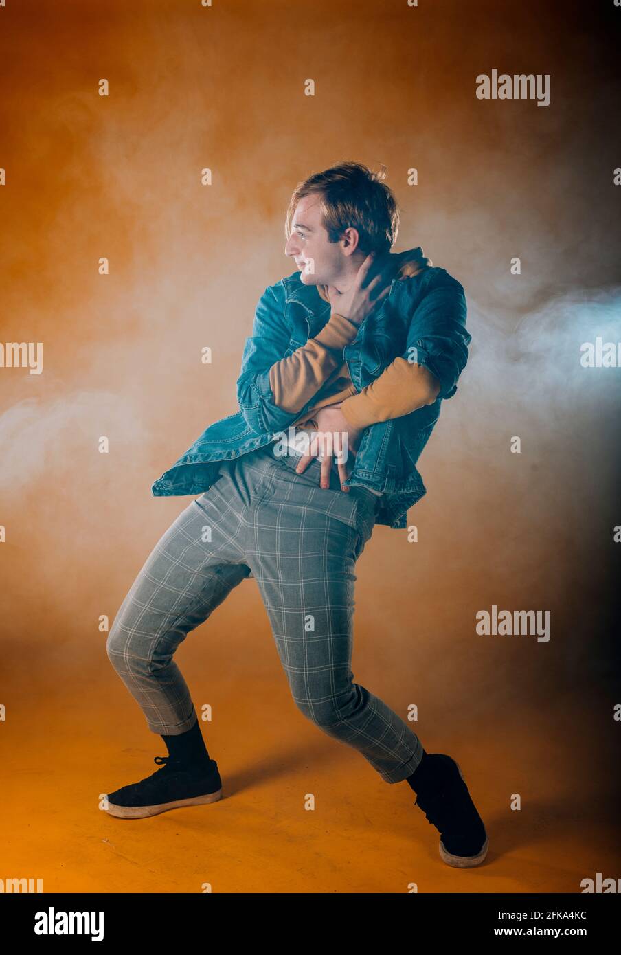 Muscular male dancer performing a dance routine in the orange studio ...