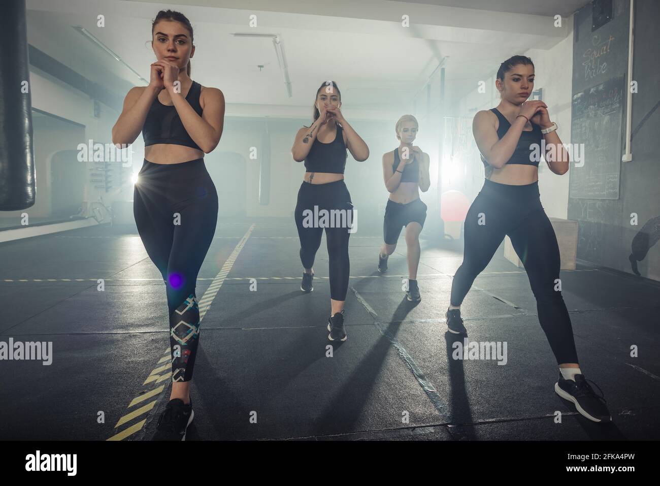 Group of sportswomen in sportswear doing lunge exercise at the gym with ...