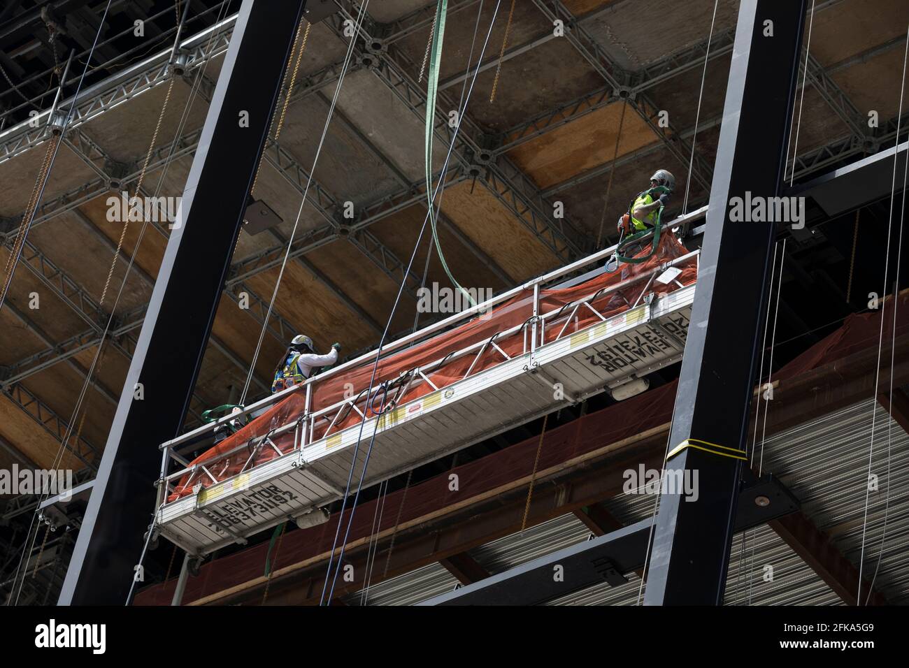 Construction workers in suspended scaffolding on the south facade of ...