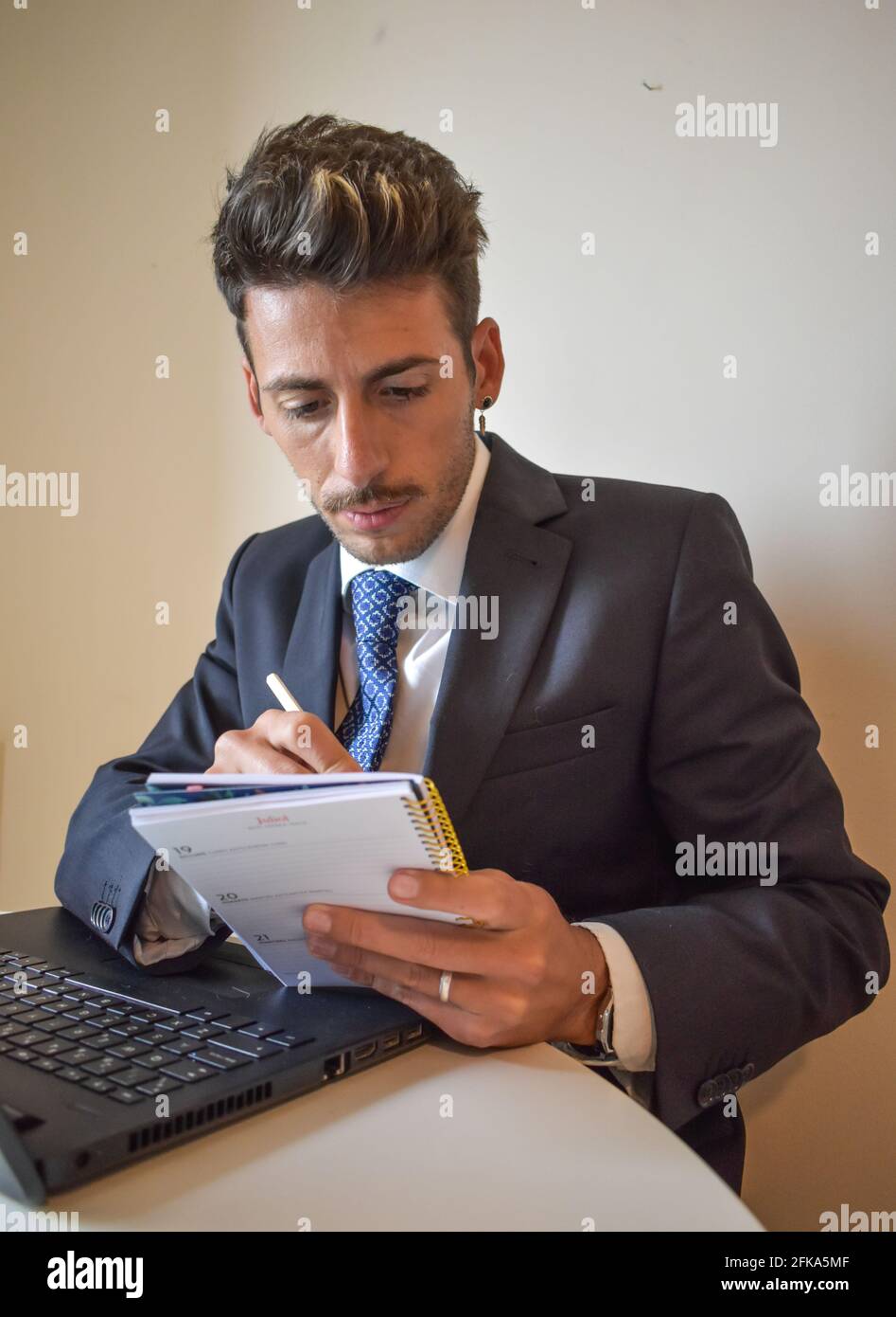 Working handsome man taking notes in the notebook while working with ...