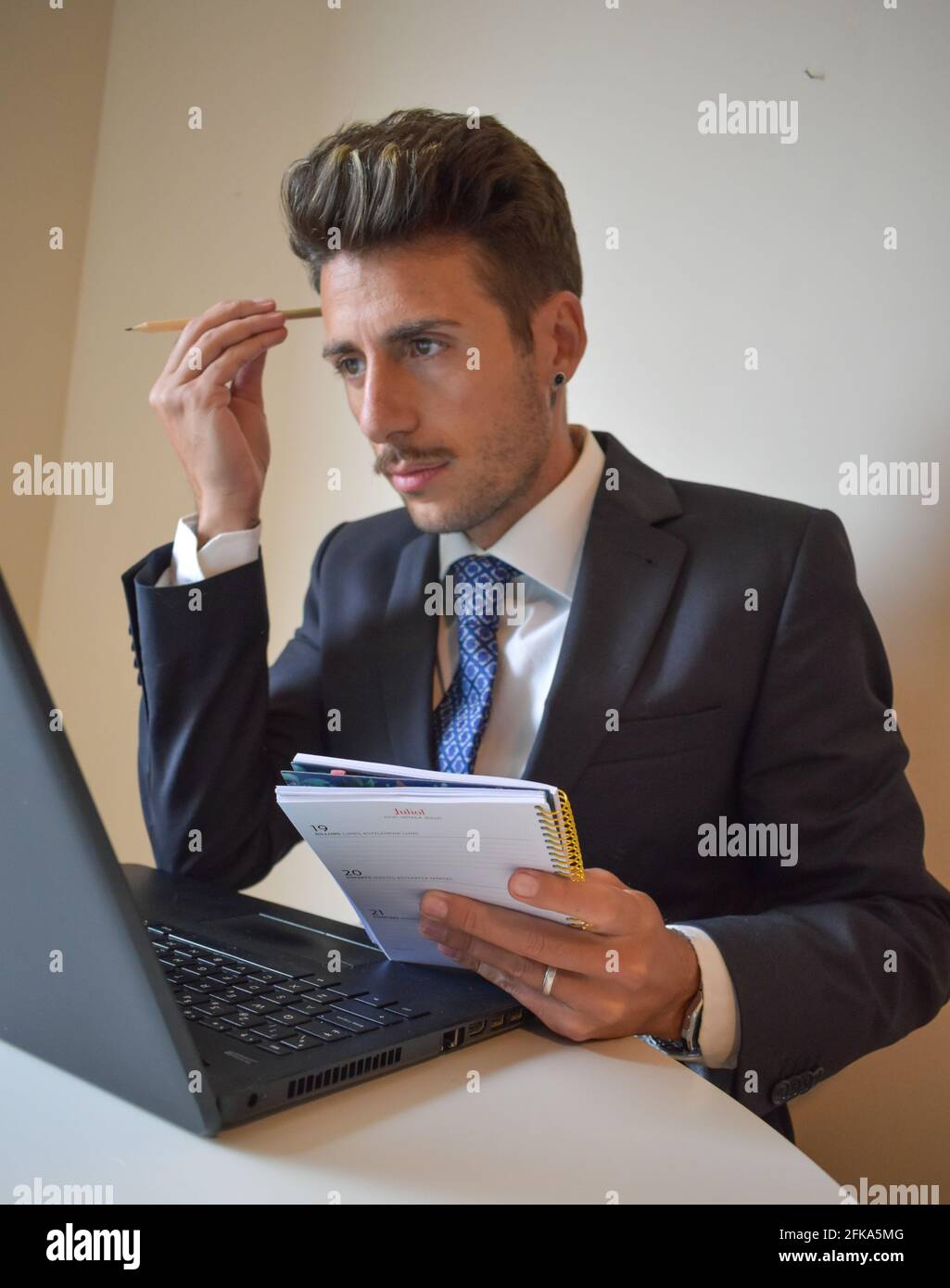 Handsome businessman thinking in front of his laptop - business concept ...