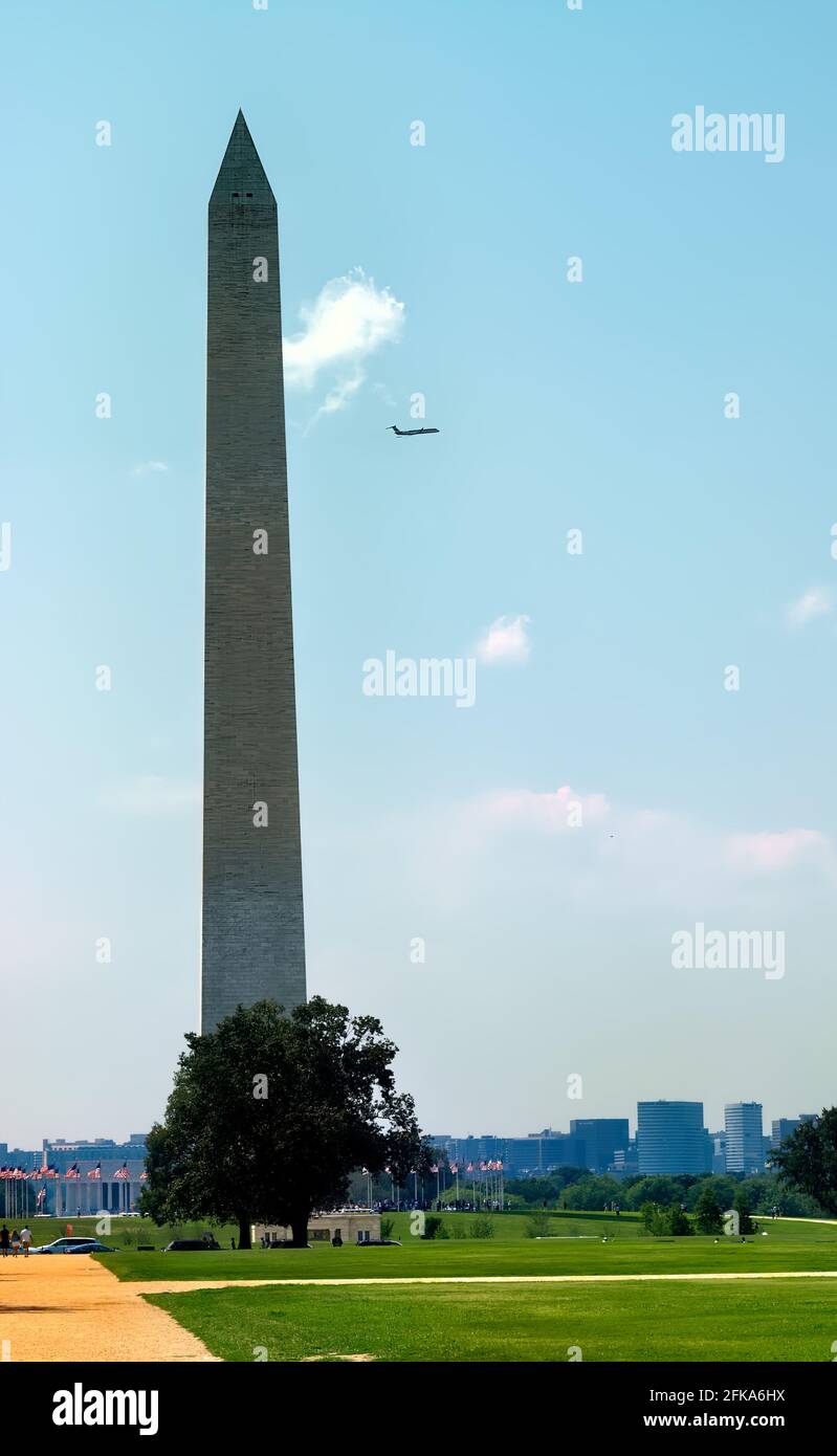 A jet plane passes in the distance behind the Washington Monument in ...
