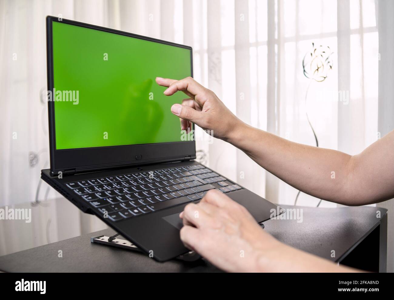 Closeup of a laptop with green screen space and a person's fingers ...