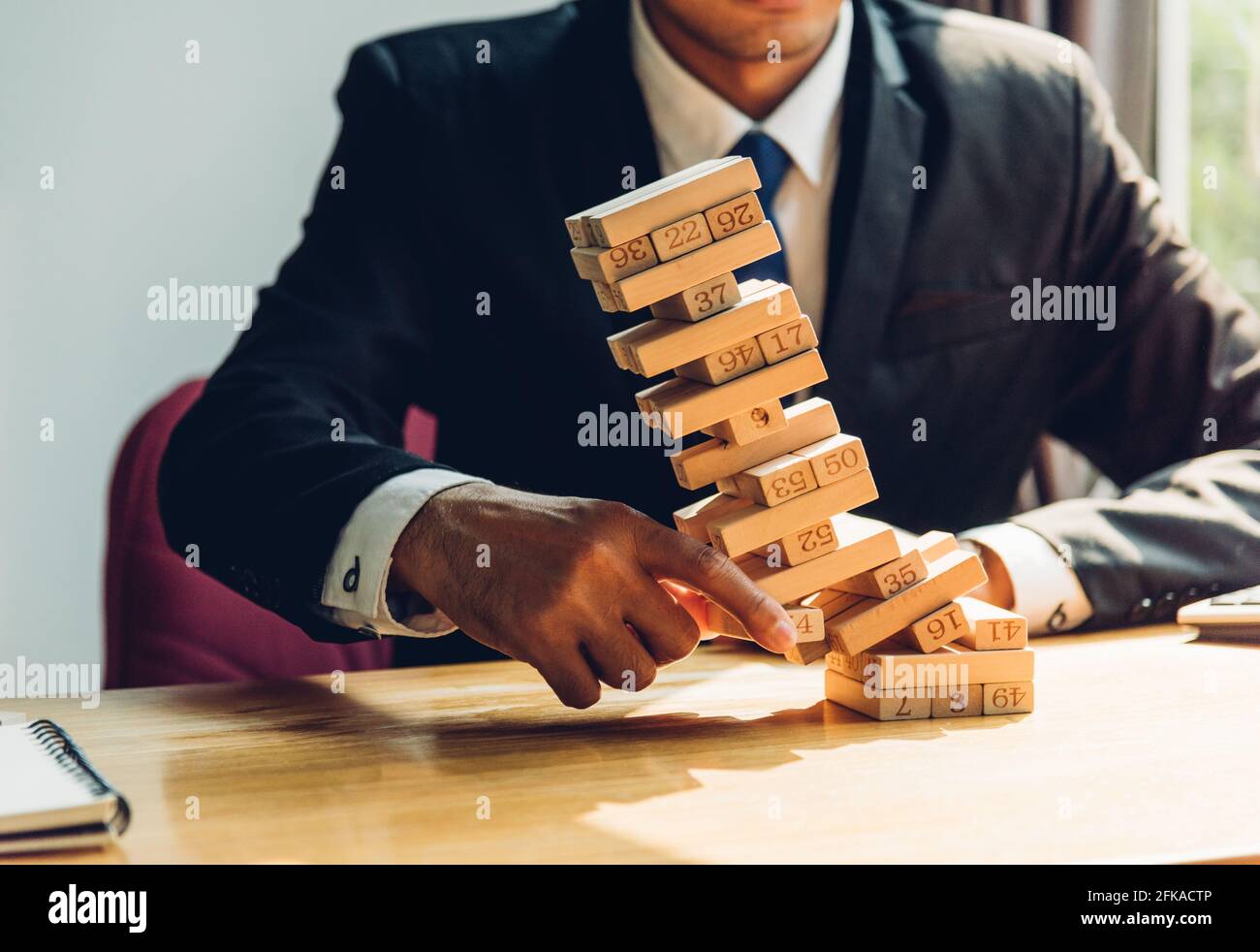 Business man challenge pulling block wood building tower, the block ...