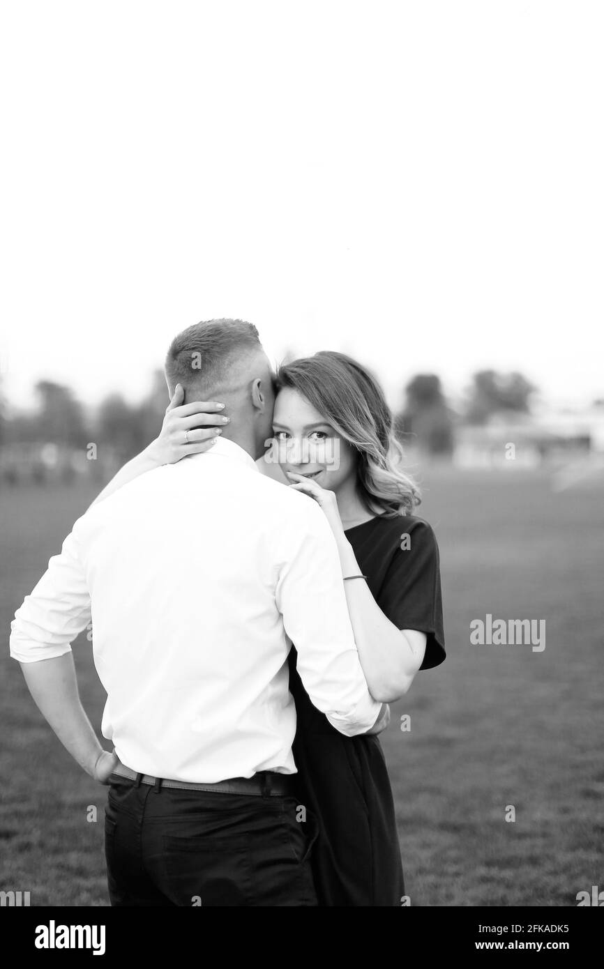Black and white photo of young woman hugging back view man on lawn ...