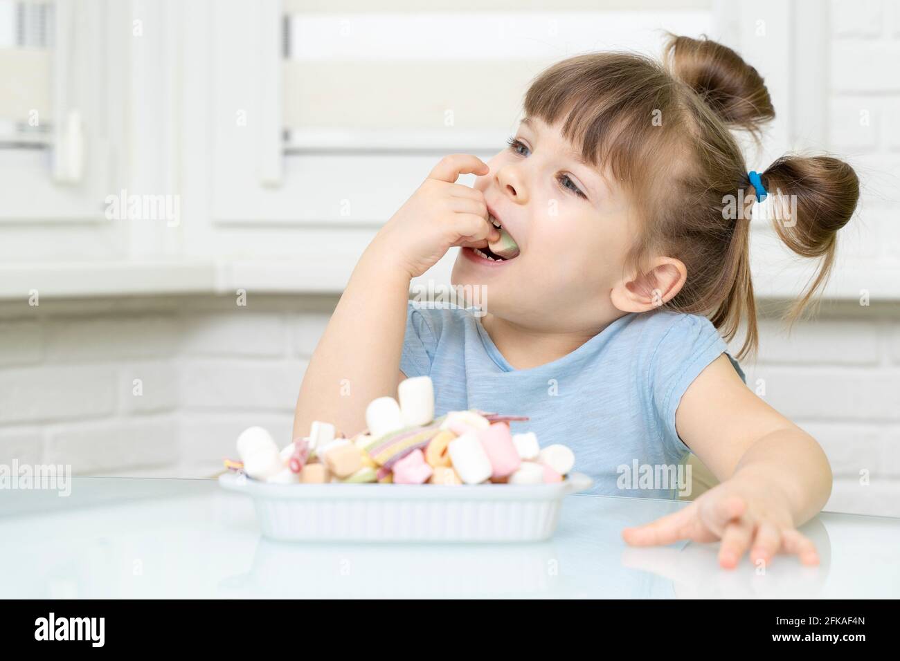 cute European female child smiling, happily eating candy, with appetite ...