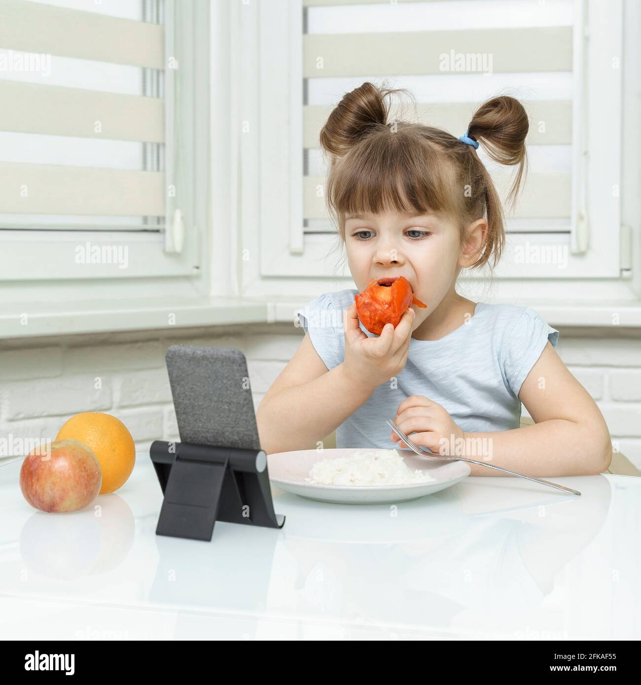 child girl eating food and watching cartoons on a smartphone Stock ...