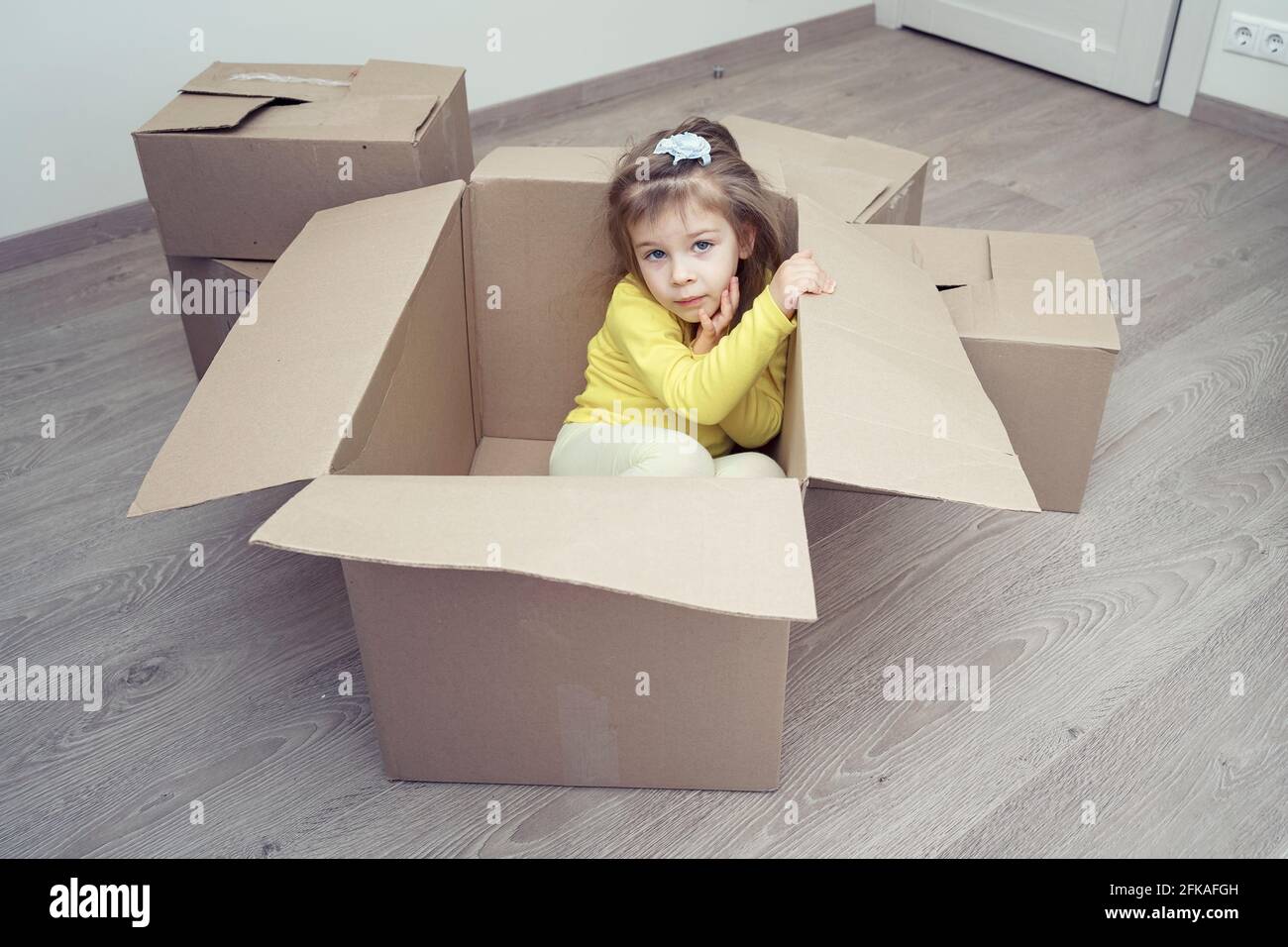 sad child girl sitting in box for moving to a new apartment Stock Photo ...