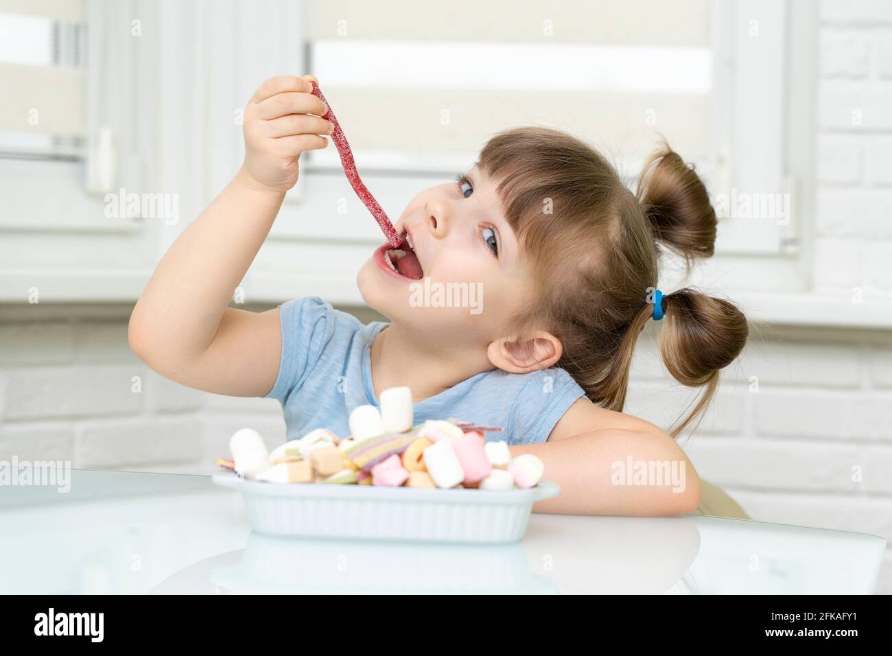 happy contented little girl eating candy from a plate full of sweets ...