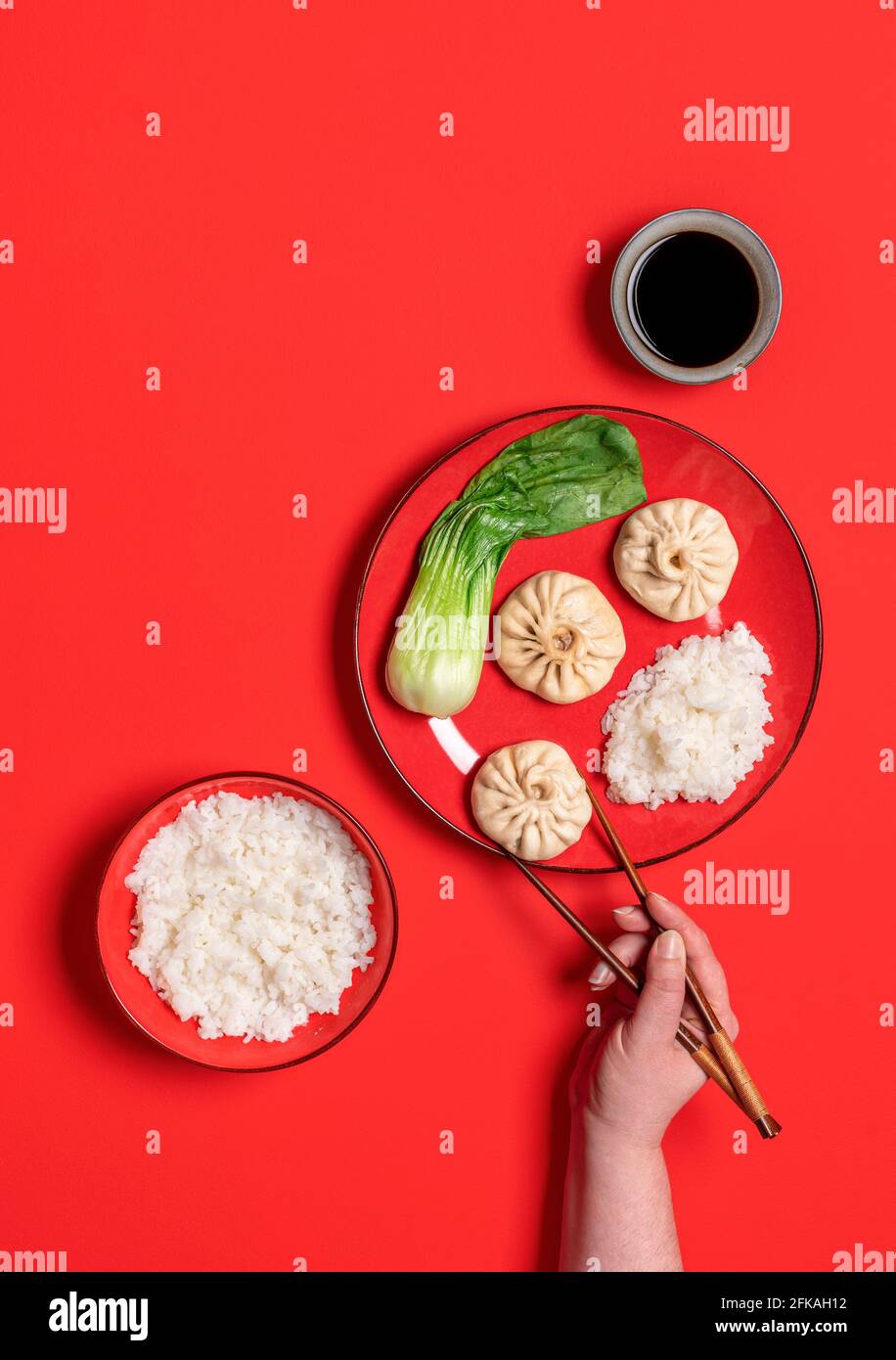 Above with a women's hand eating asian food using wooden chopsticks ...