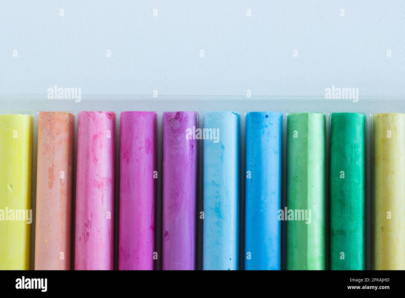 Close up of a row of colorful chalks isolated on white background with ...