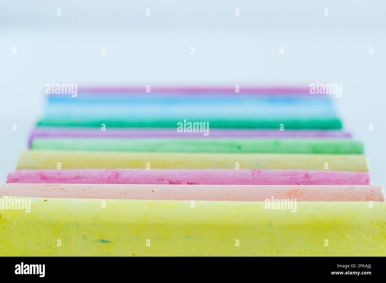 Close up of a row of colorful chalks isolated on white background with ...