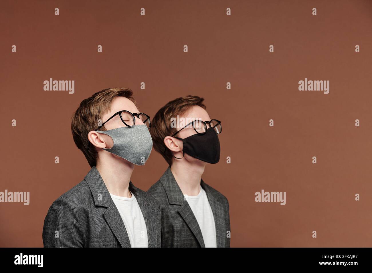 Side view of calm twins in facial masks and glasses trying to breath ...