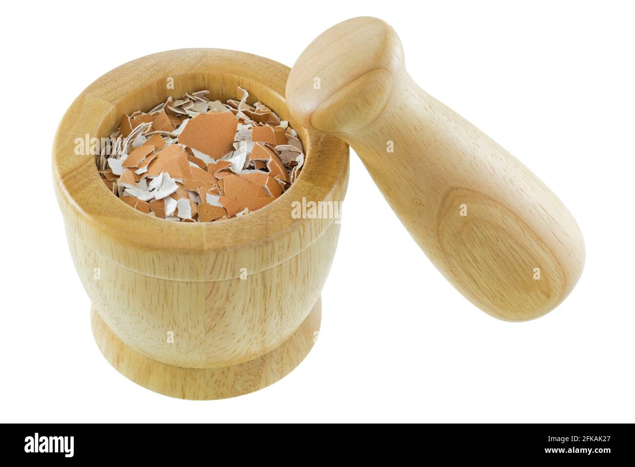 Crushed Chicken egg shells inside wooden mortar next to pestle ...