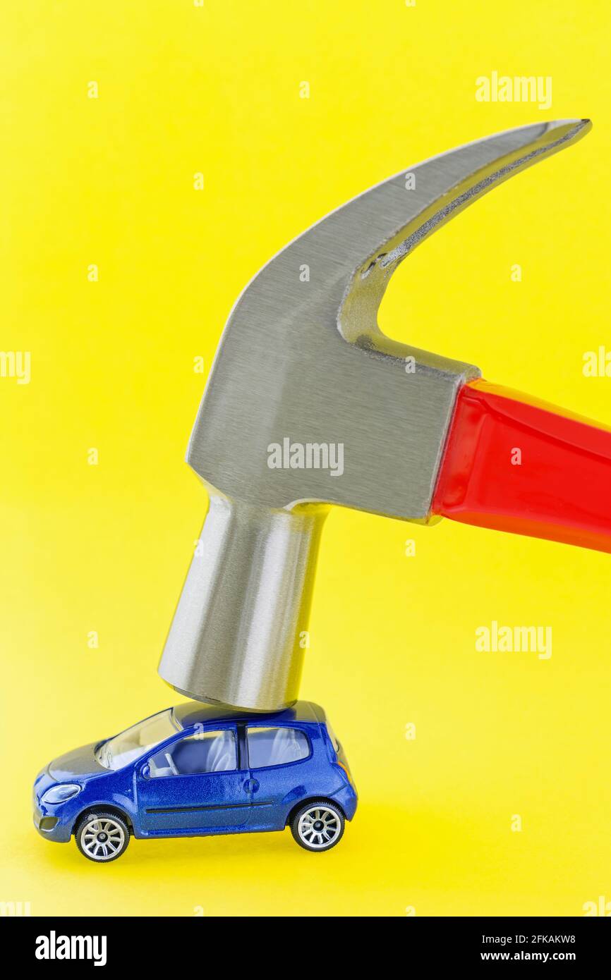 Steel claw hammer with red handle hitting on mini blue car on yellow ...