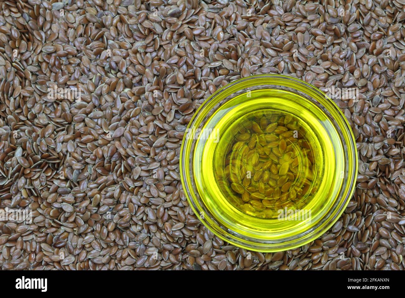 A bowl of cold pressed Linseed yellow oil on flaxseed background ...