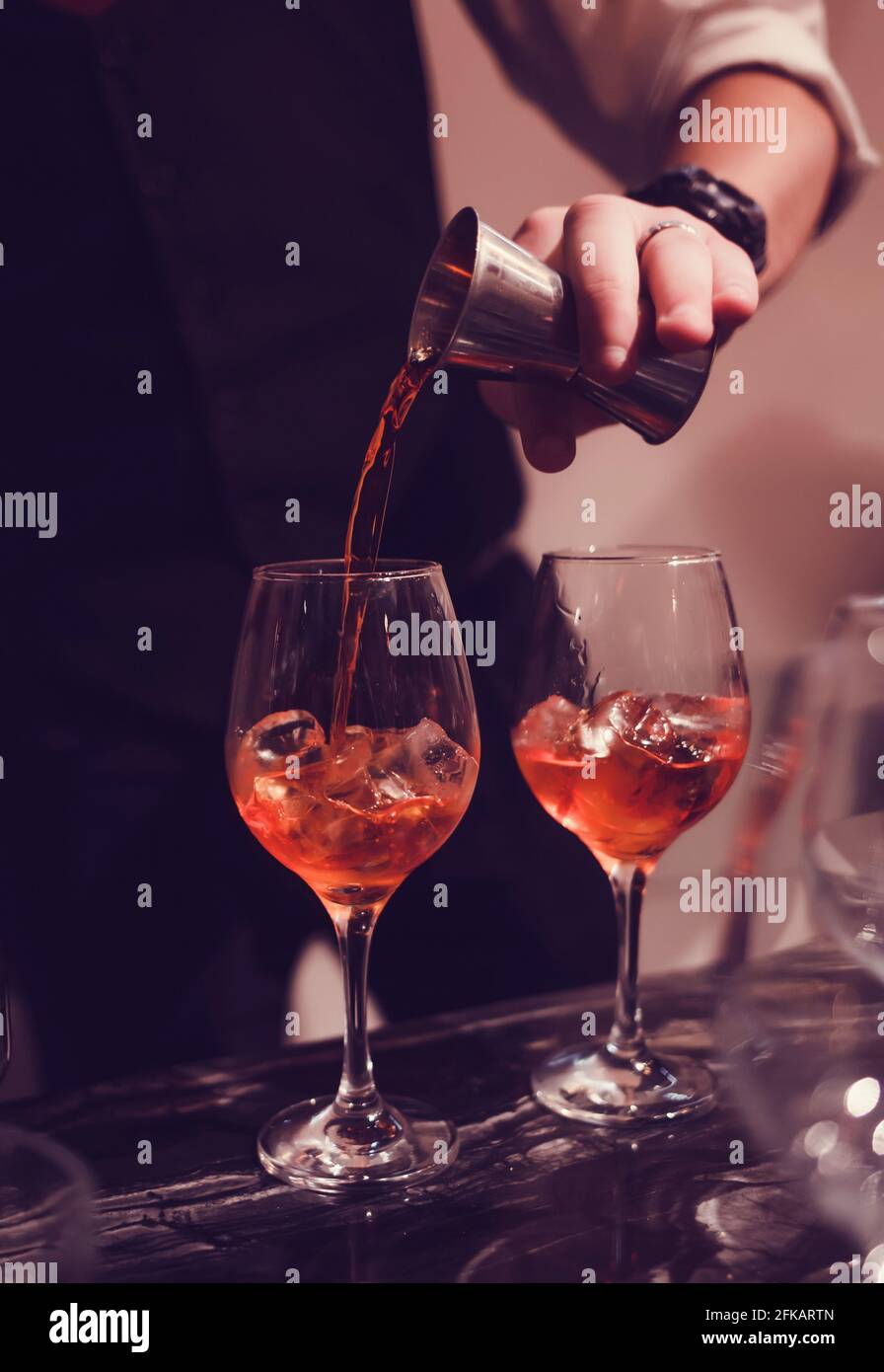 the bartender pours sweet syrup into a glass with ice makes an ...