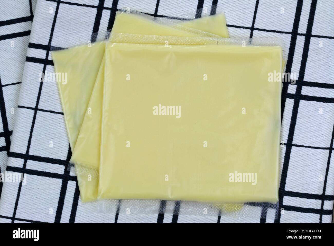 Processed Cheddar Cheese in individual wrapped slides, on a checked ...