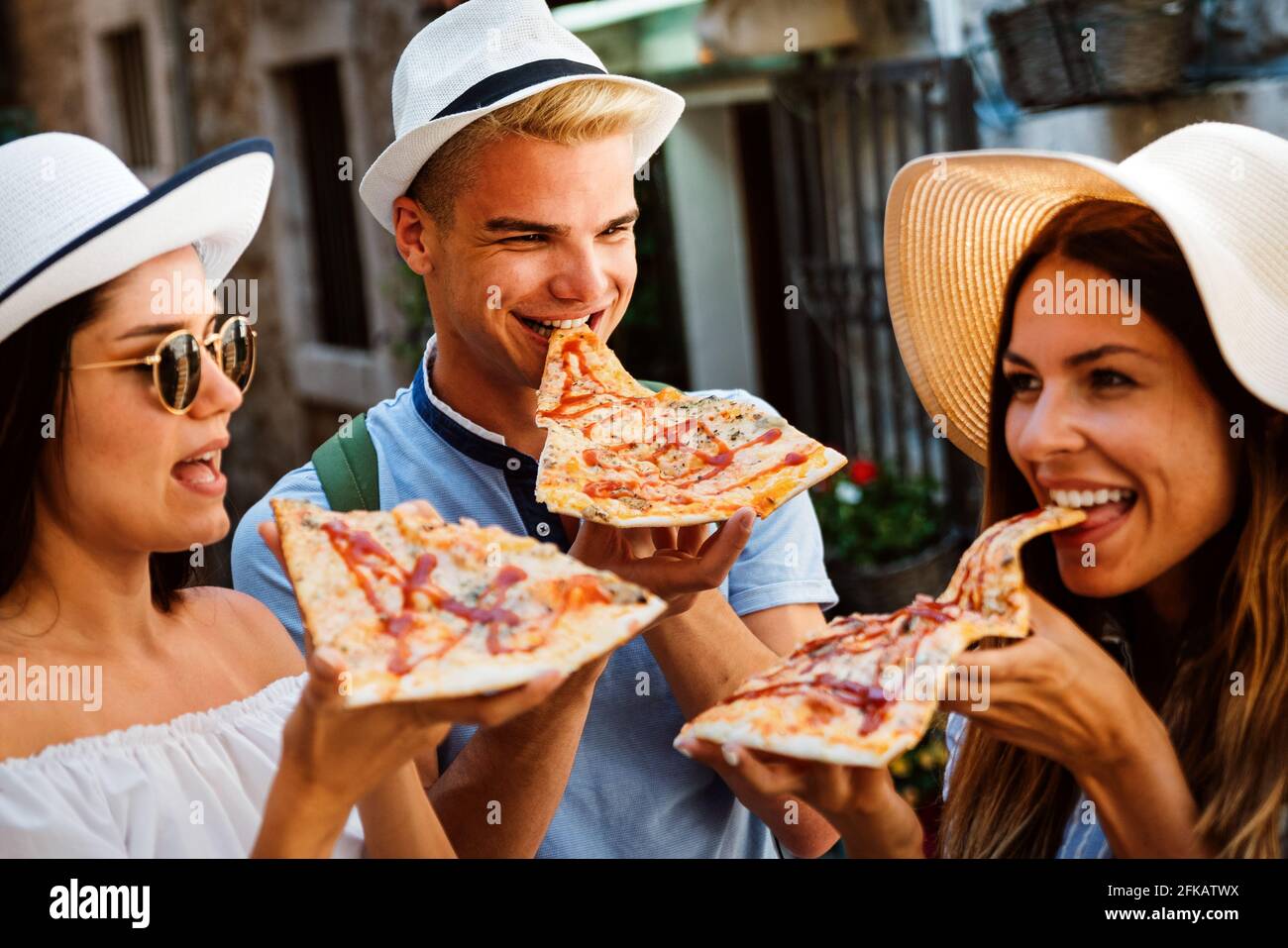 Happy traveling tourists friends having fun, eating pizza on summer ...