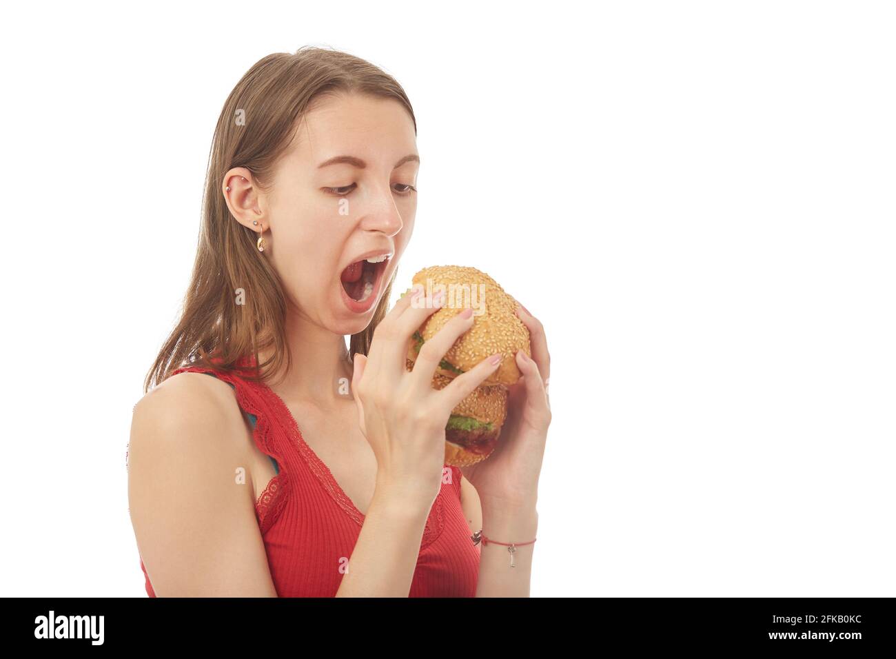 happy young woman eats cheeseburger on white background isolated ...